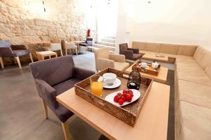 Uma área de estar moderna com parede de pedra, assentos confortáveis e uma bandeja com itens de café da manhã.