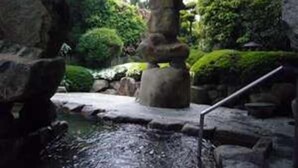 Uma ponte de pedra sobre um pequeno riacho, em um jardim.
