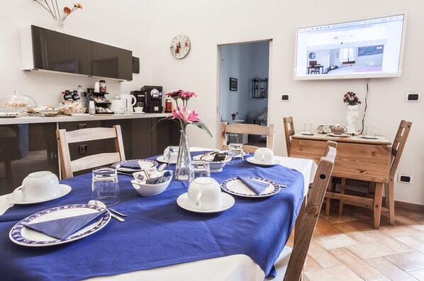 Uma área de refeições com toalha de mesa azul, pratos brancos e um vaso com flores.