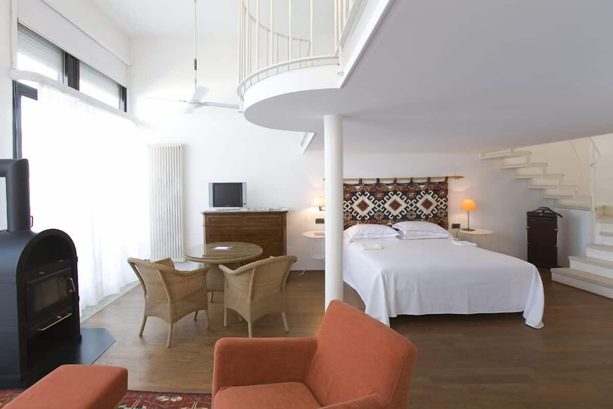 Quarto de hotel moderno com cama, televisão, lareira e varanda.