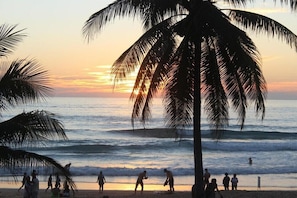 Uma praia com palmeiras e pessoas na orla.