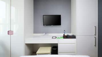 Quarto de hotel com cama, secretária, televisão de tela plana, lixeira e armário.