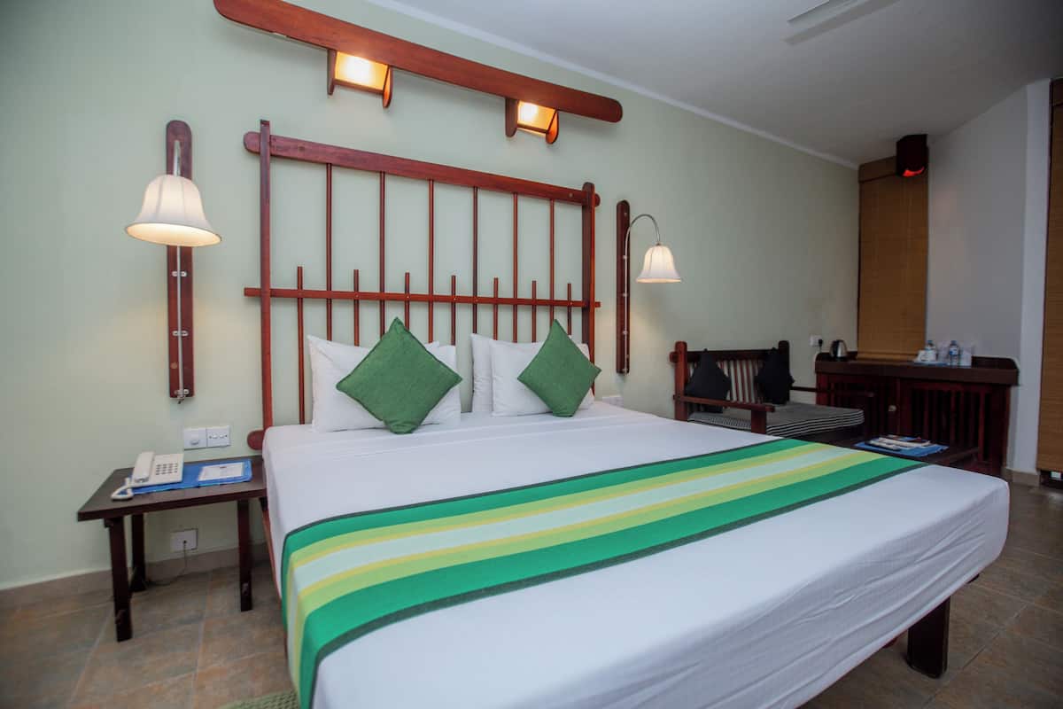 Quarto de hotel com cama, abajures, mesa de cabeceira, escrivaninha e uma cadeira.