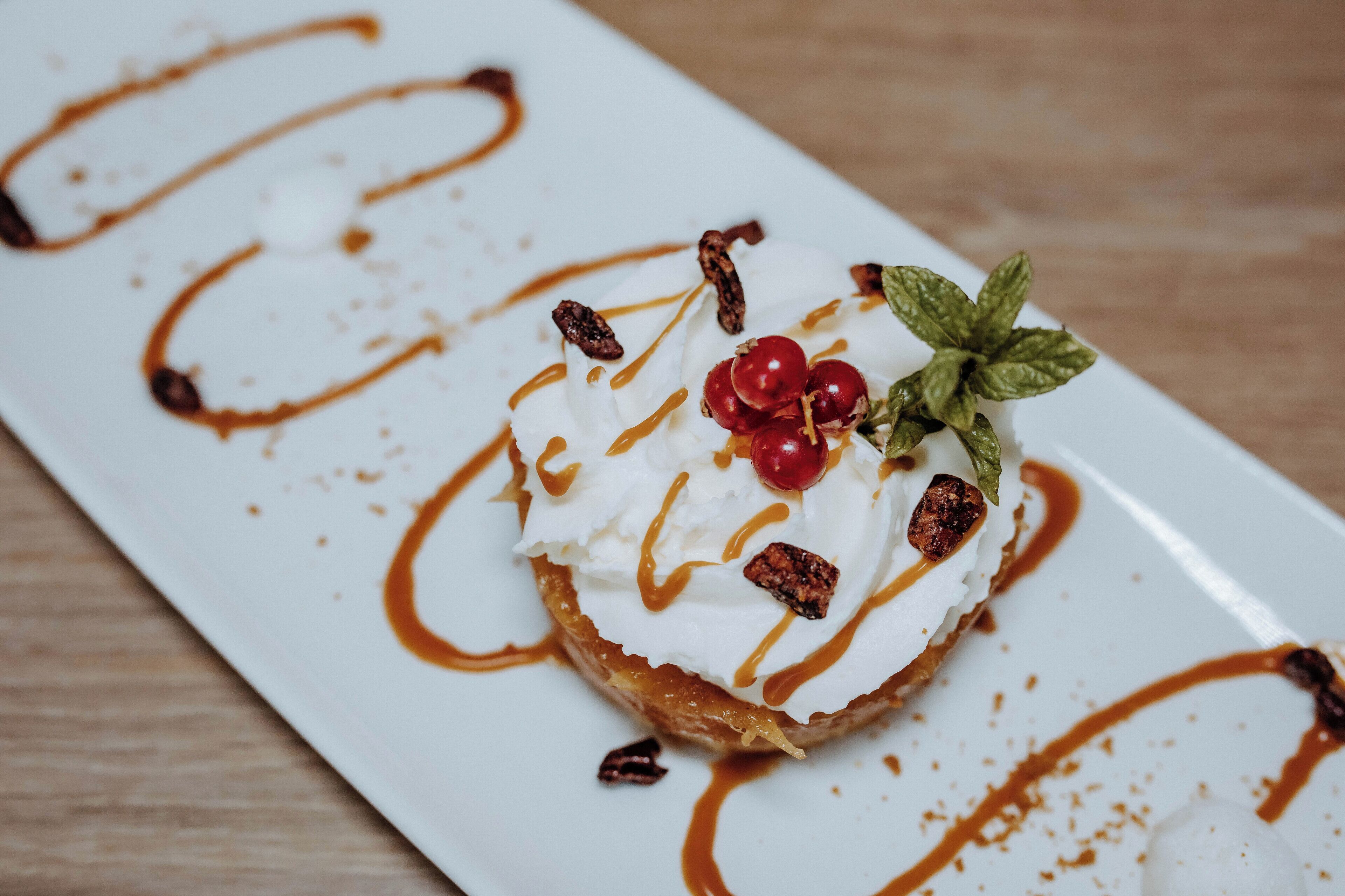 Sobremesa em um prato branco com fio de caramelo e guarnições.
