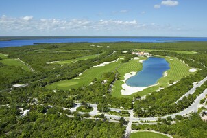Um campo de golfe com vários buracos, armadilhas de areia e uma grande massa de água.