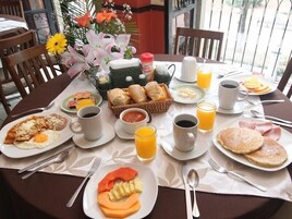Uma mesa de café da manhã com diversos pratos, incluindo ovos, panquecas e frutas.