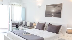 Quarto moderno com uma cama grande, um sofá, uma mesa de centro de vidro e uma luminária na parede.