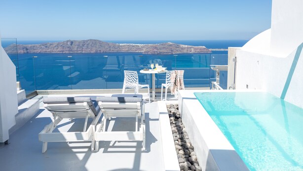 Terraço no telhado com piscina, espreguiçadeiras e uma mesa com bebidas, com vista para a paisagem costeira.