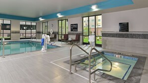 Uma área moderna de piscina coberta, com sinalização clara, incluindo um aviso de 'Sem salva-vidas no local', e uma piscina rasa separada com um indicador de profundidade de 3 pés.