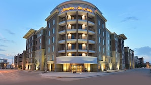 Um hotel com vários andares e fachada curva, com várias varandas e uma placa visível de Hampton Inn & Suites.