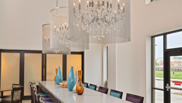 Uma área de refeições moderna com uma grande ilha, diversas cadeiras e um candelabro.