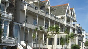 Um edifício de vários andares com varandas, escadas e palmeiras.