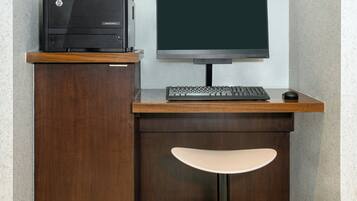 Um espaço de escritório compacto com uma impressora HP, um monitor, um teclado e uma cadeira.
