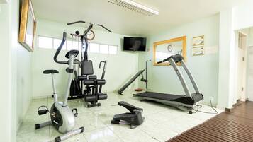 Academia com equipamentos de ginástica, incluindo esteira, elíptico e aparelhos de musculação.