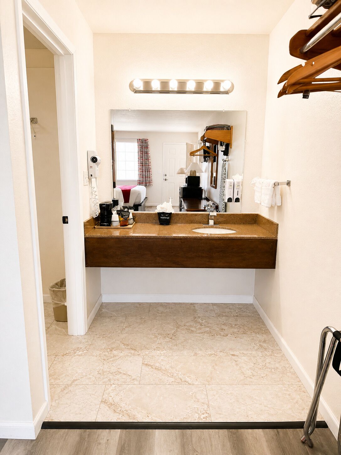 Casa de banho com lavatório, espelho, secador de cabelo e porta-toalhas.