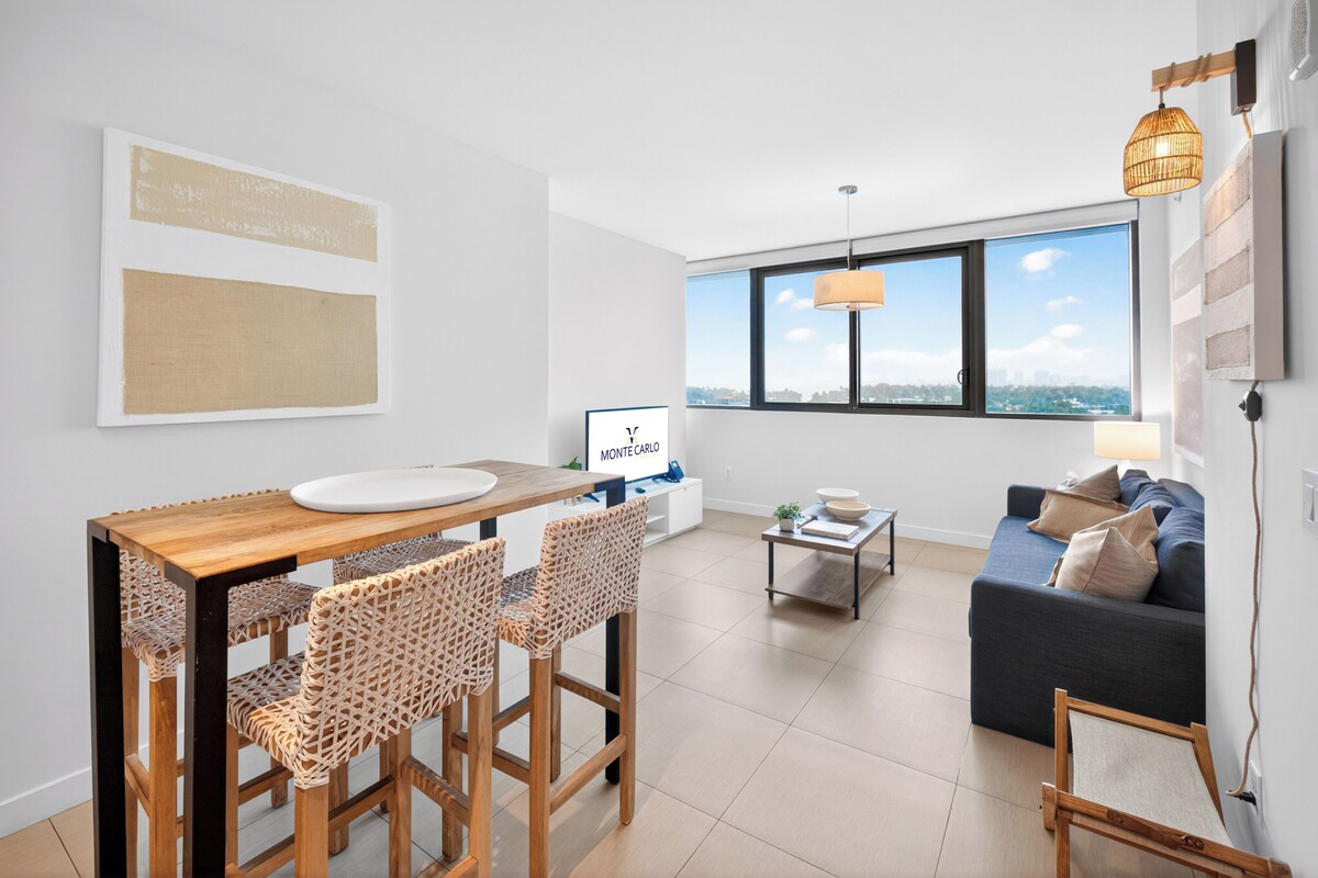 Uma sala de estar moderna com área de jantar, um sofá e vista para a cidade.