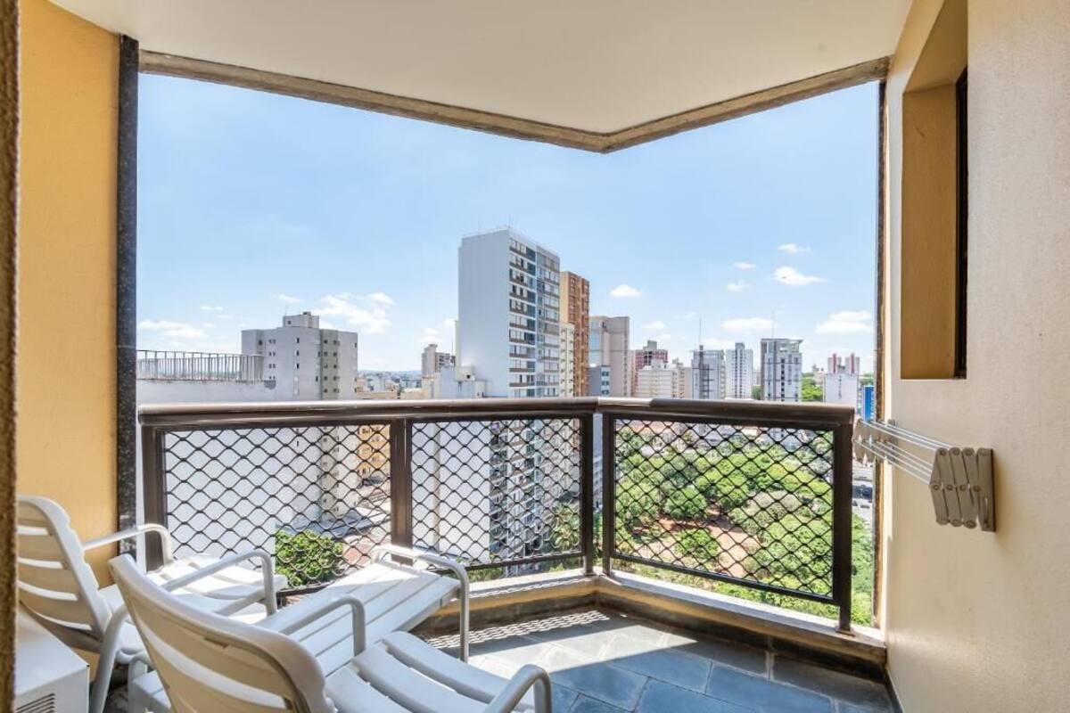 Uma varanda com vista para um horizonte urbano, incluindo edifícios altos e uma área verde com parque.