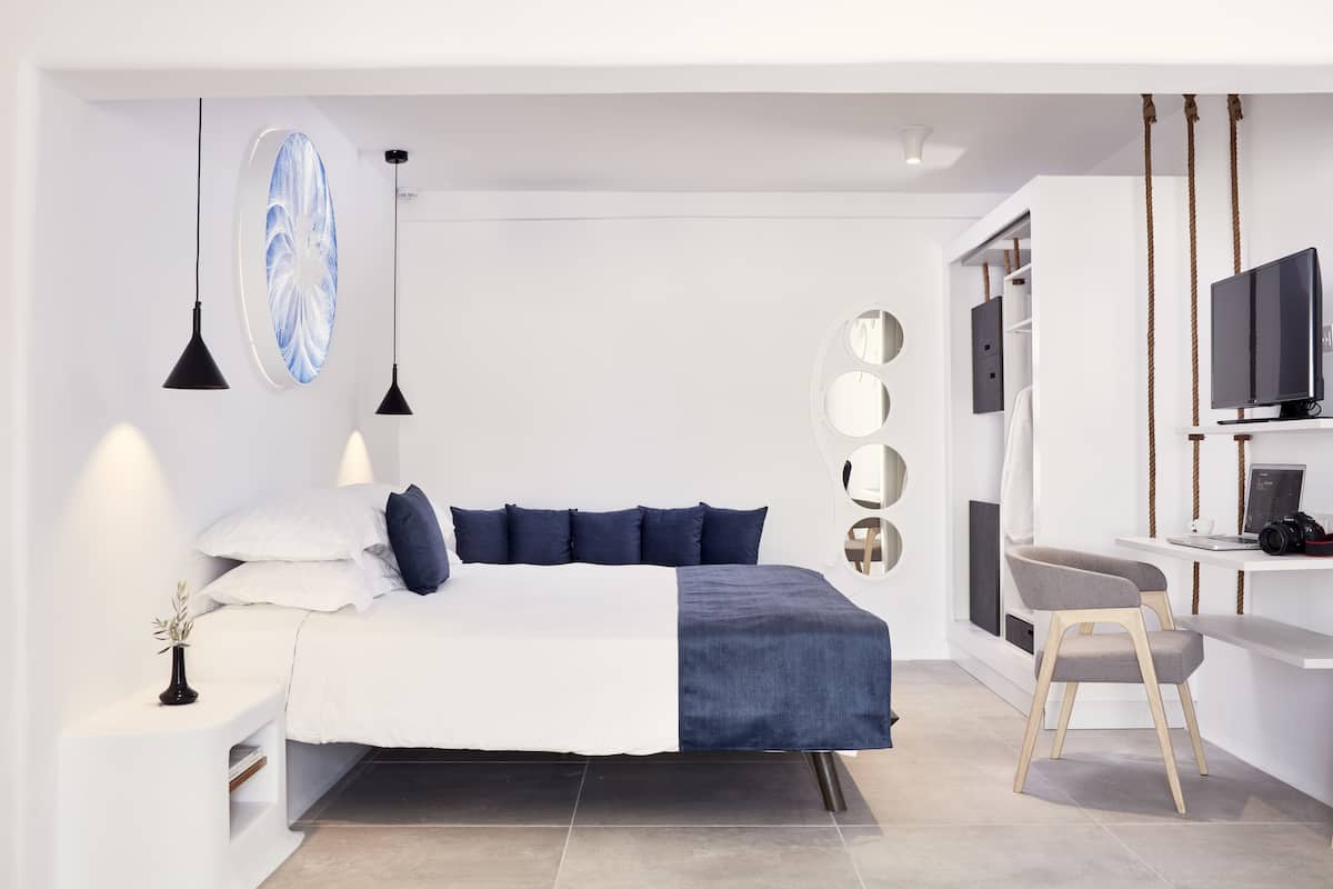 Um quarto moderno com uma cama, mesas de cabeceira, escrivaninha e uma cadeira.