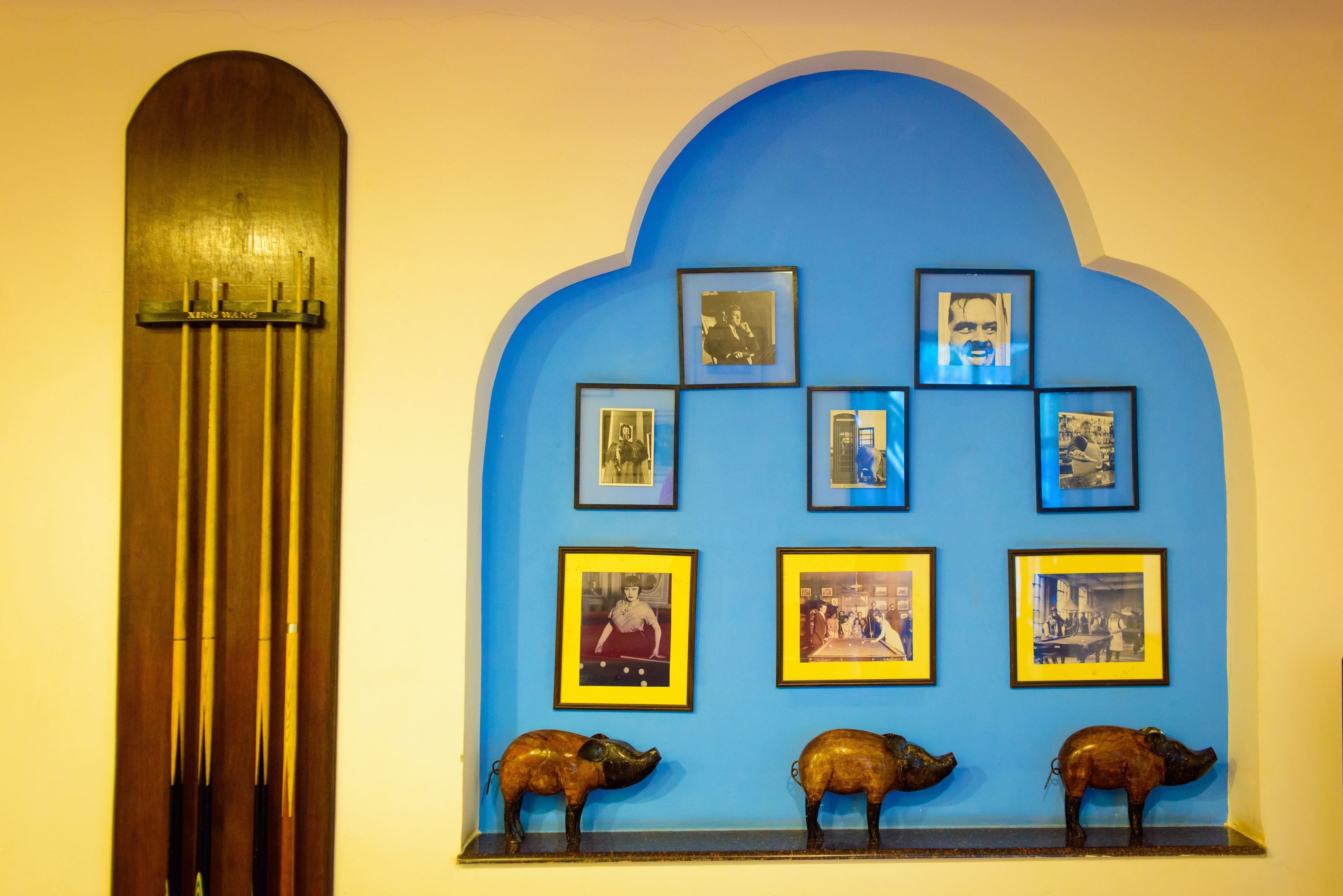 Pared com fotografias emolduradas e duas esculturas de porco.