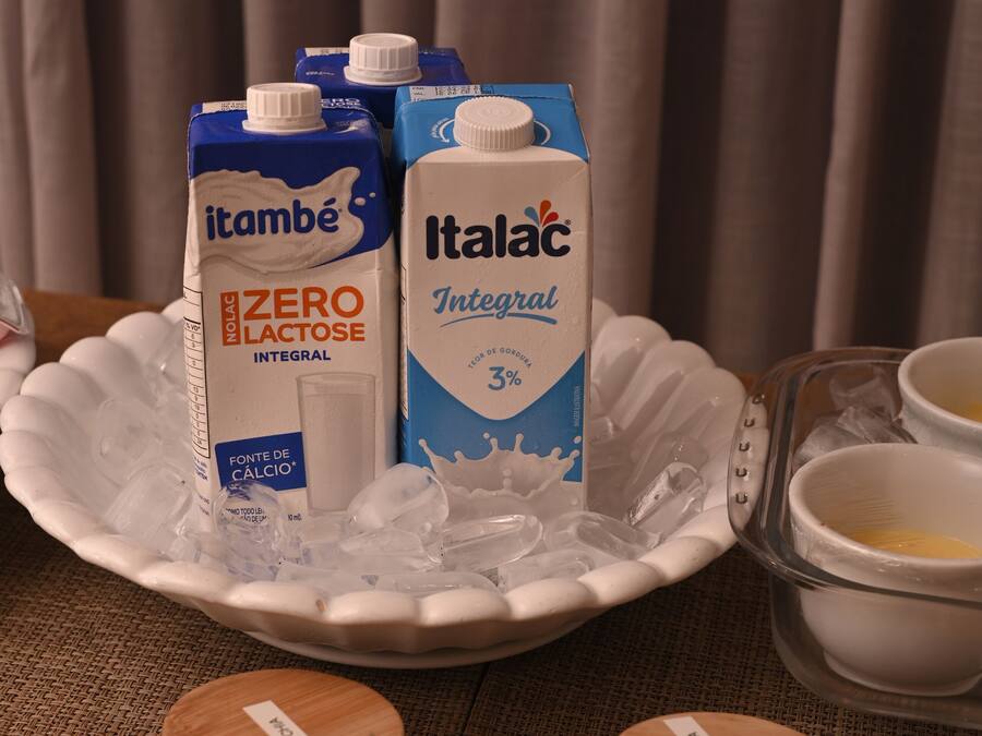 Uma mesa com dois caixas de leite, uma tigela e recipientes de madeira com grãos.