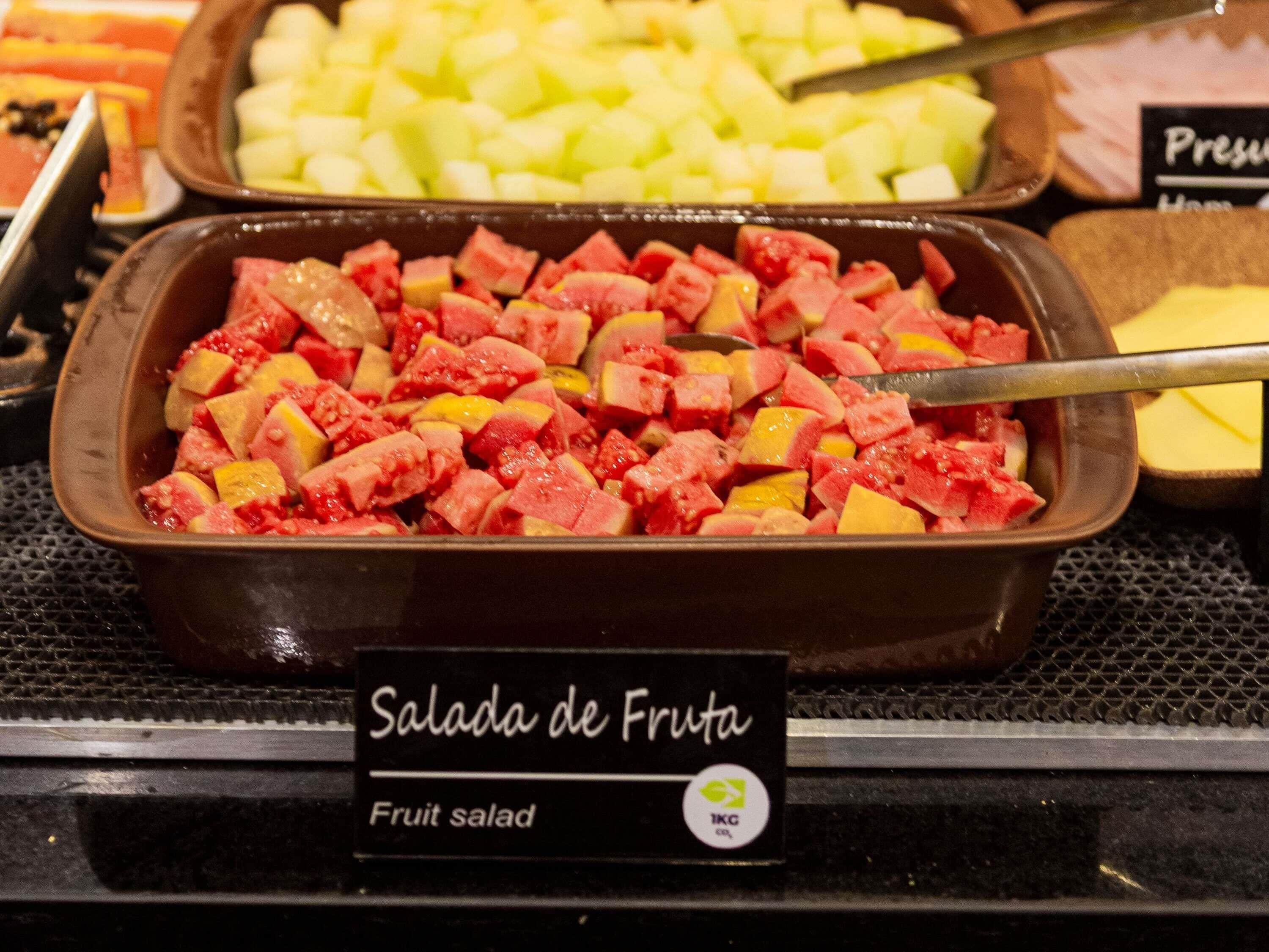 Exposição de diferentes saladas de frutas em uma seção de frios.