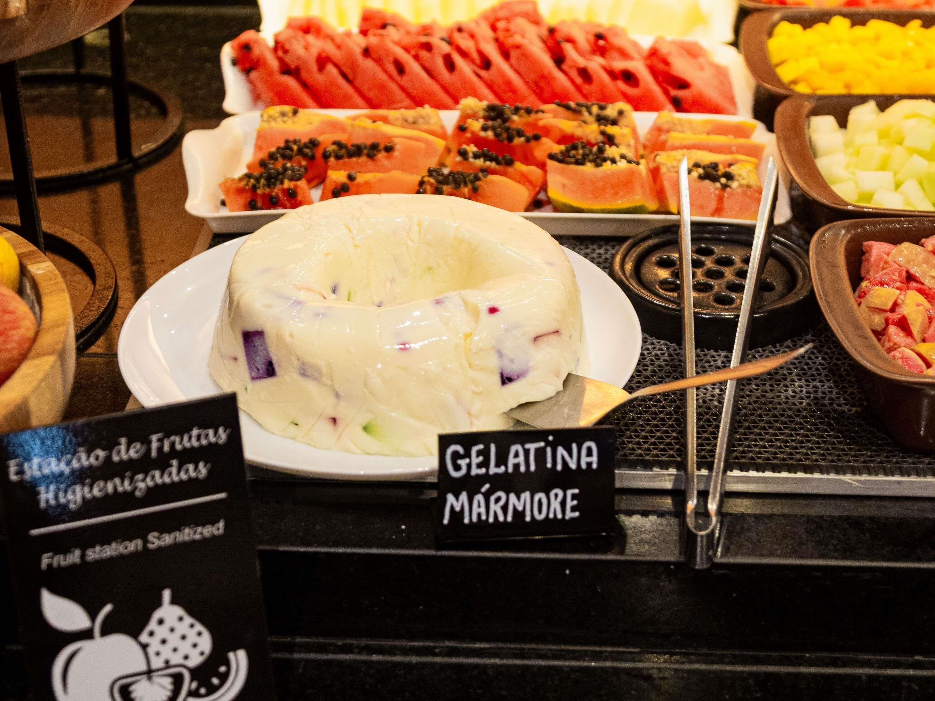 Exposição de frutas diversas e um prato de gelatina marmorizada.