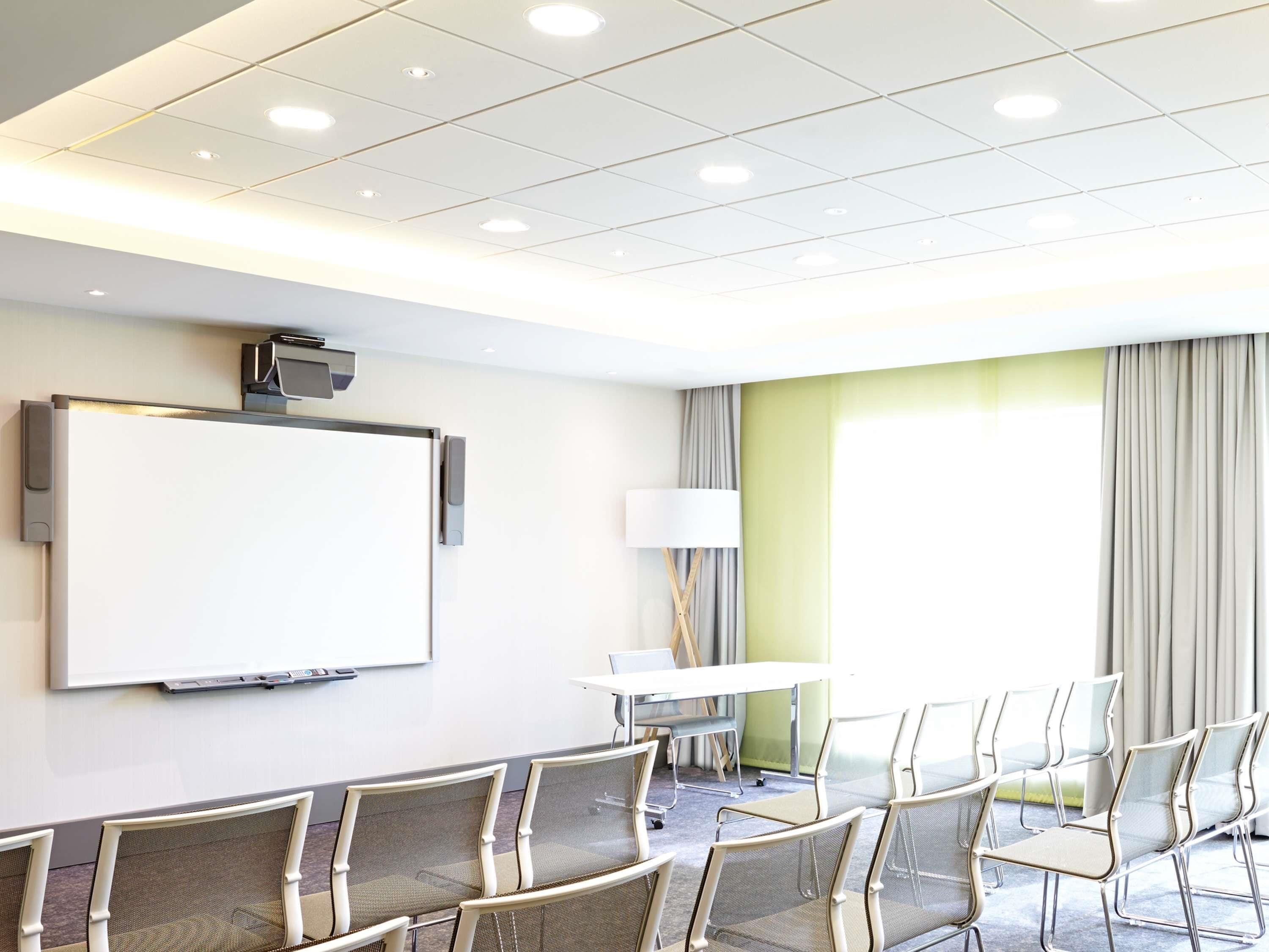 Uma sala de conferência com quadro branco, projetor, mesa e cadeiras.