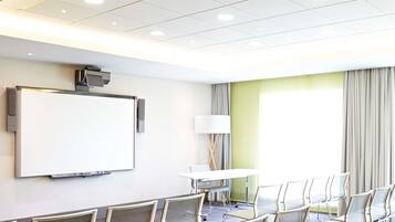 Uma sala de conferência com quadro branco, projetor, mesa e cadeiras.