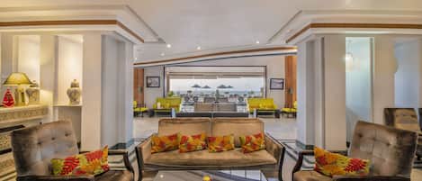 Um hall amplo com poltronas de couro, um sofá e uma mesa de centro de vidro.