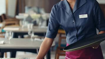 Uma pessoa vestindo uniforme serve uma mesa com um copo e um prato.