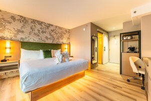 Quarto de hotel moderno com uma cama grande, luminárias de cabeceira, uma escrivaninha e uma cadeira.
