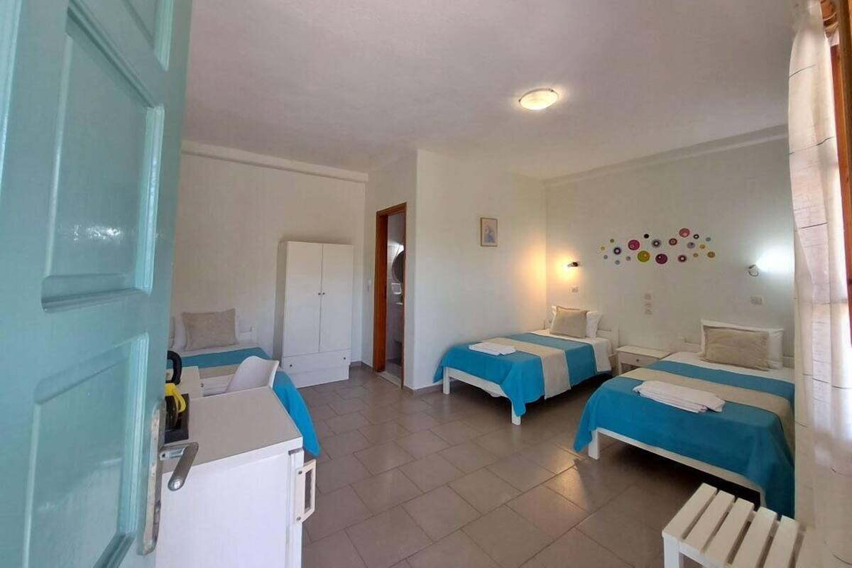 Quarto com duas camas, uma escrivaninha e um guarda-roupa.