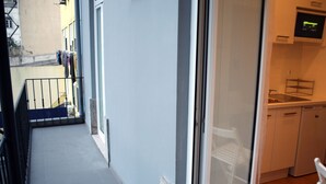 Um corredor estreito com chão de azulejos, conduzindo a uma porta de vidro.