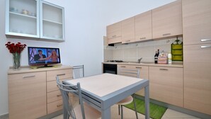 Uma cozinha moderna com armários de madeira clara, fogão a gás e um espaço de jantar com mesa e cadeiras.