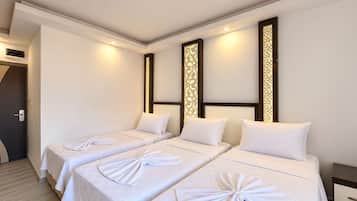 Quarto de hotel com duas camas, cada uma com uma toalha dobrada em laço.
