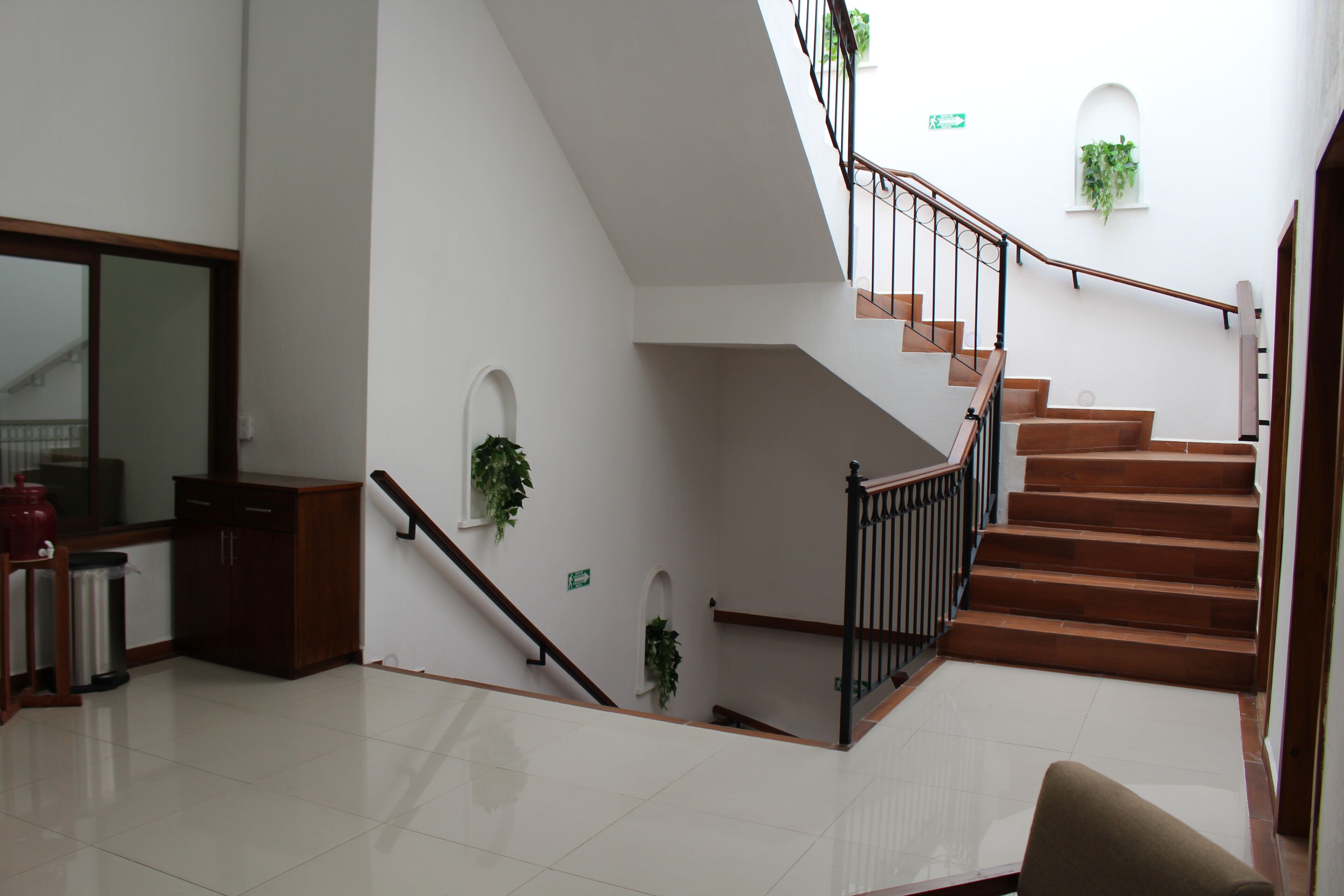 Uma sala de estar ampla com escada, piso de madeira e vista para o exterior.