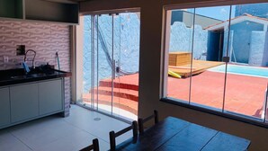 Cozinha moderna com área de jantar e grandes janelas com vista para uma área de piscina.