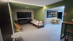 Uma sala de estar moderna com sofá, cadeiras, uma mesinha e vista para o exterior.