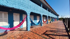 Um edifício com paredes azuis e portas brancas, com um caminho de tijolos e redes coloridas.