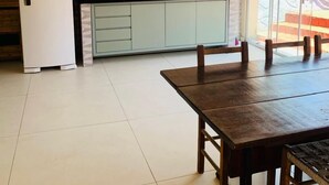 Uma cozinha com geladeira branca, mesa de madeira e janela com vista para um edifício.