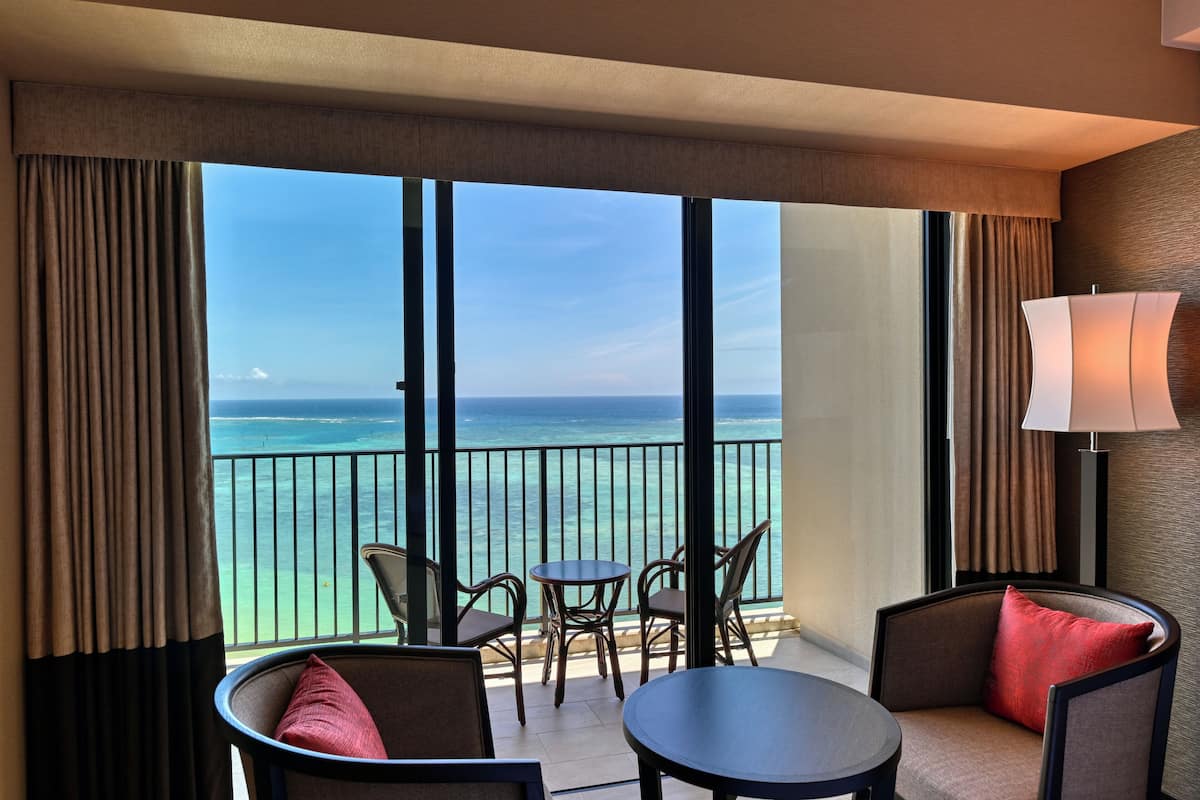 Varanda com vista para o oceano, mobiliada com cadeiras e uma mesa.