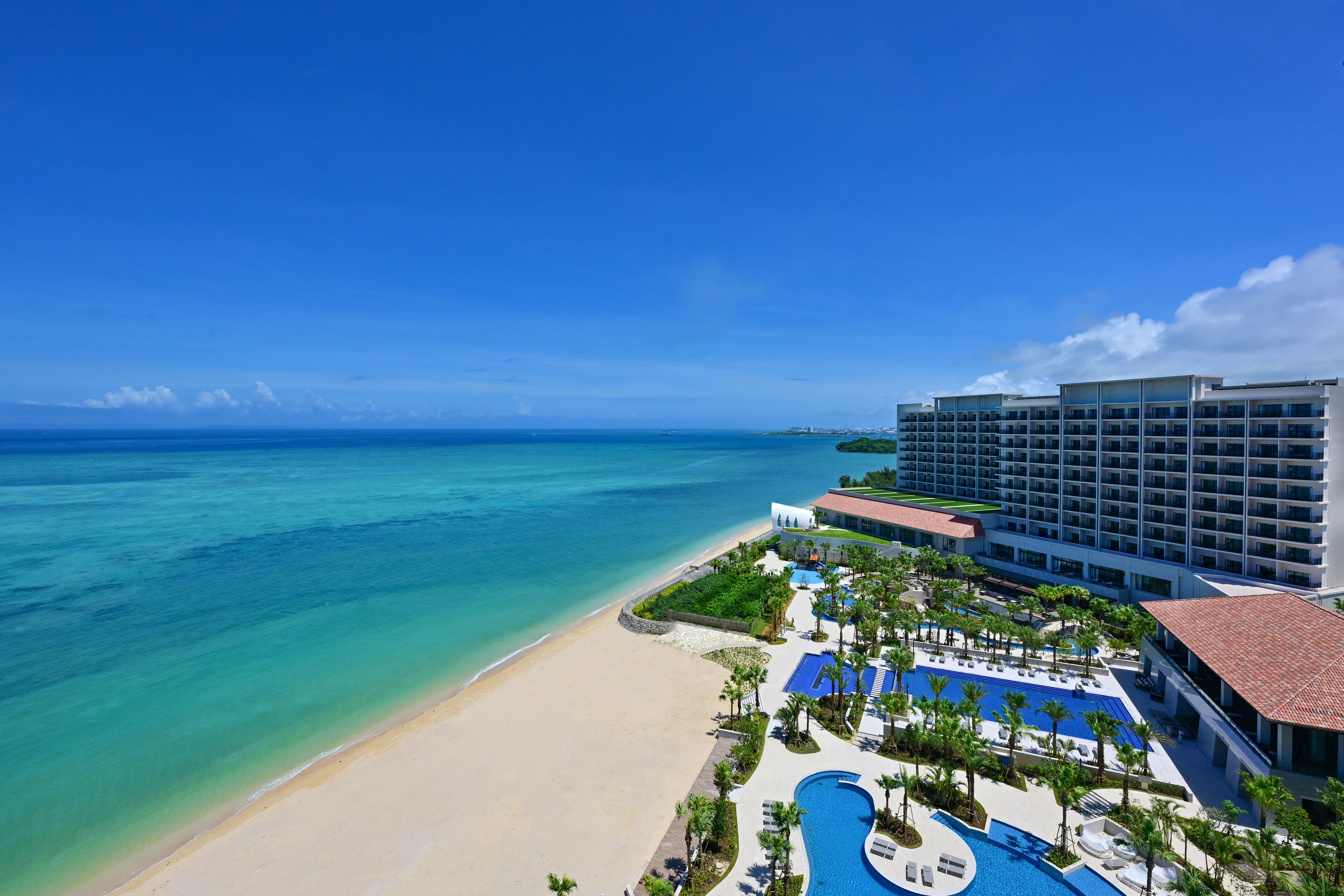 Um resort com praia, uma piscina grande e um edifício de hotel.