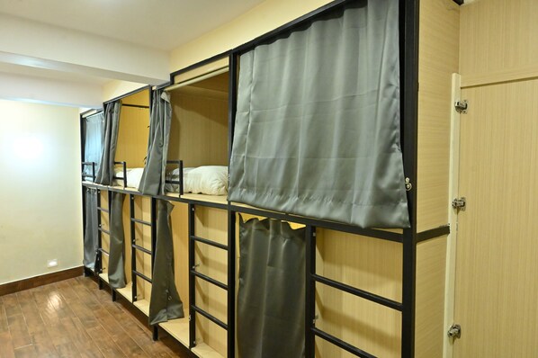 Quarto de dormitório com beliches, piso de madeira e porta com tranca.