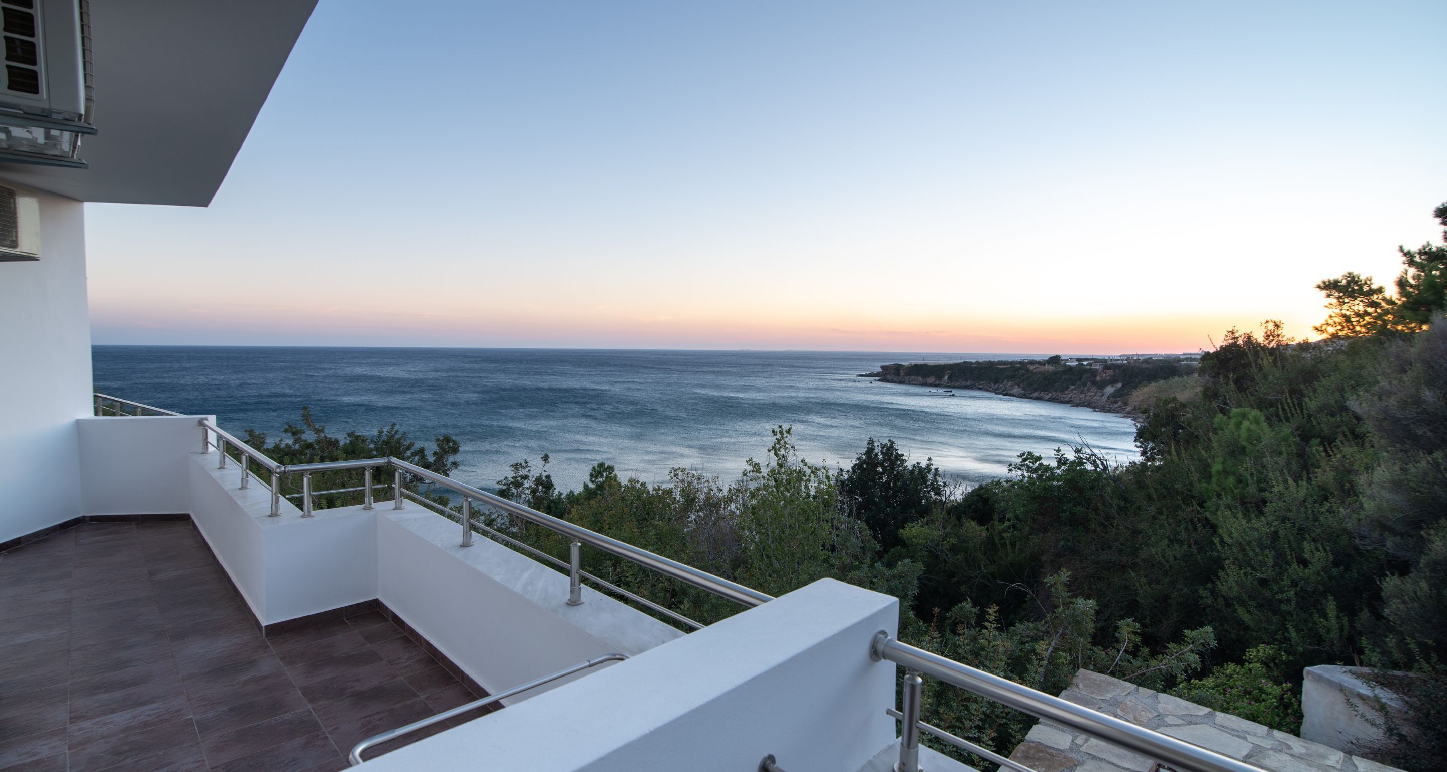 Uma varanda com vista para o mar e uma costa rochosa.