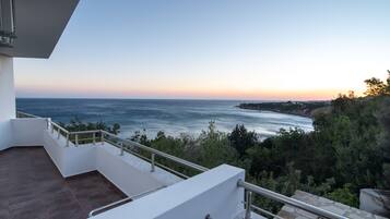 Uma varanda com vista para o mar e uma costa rochosa.
