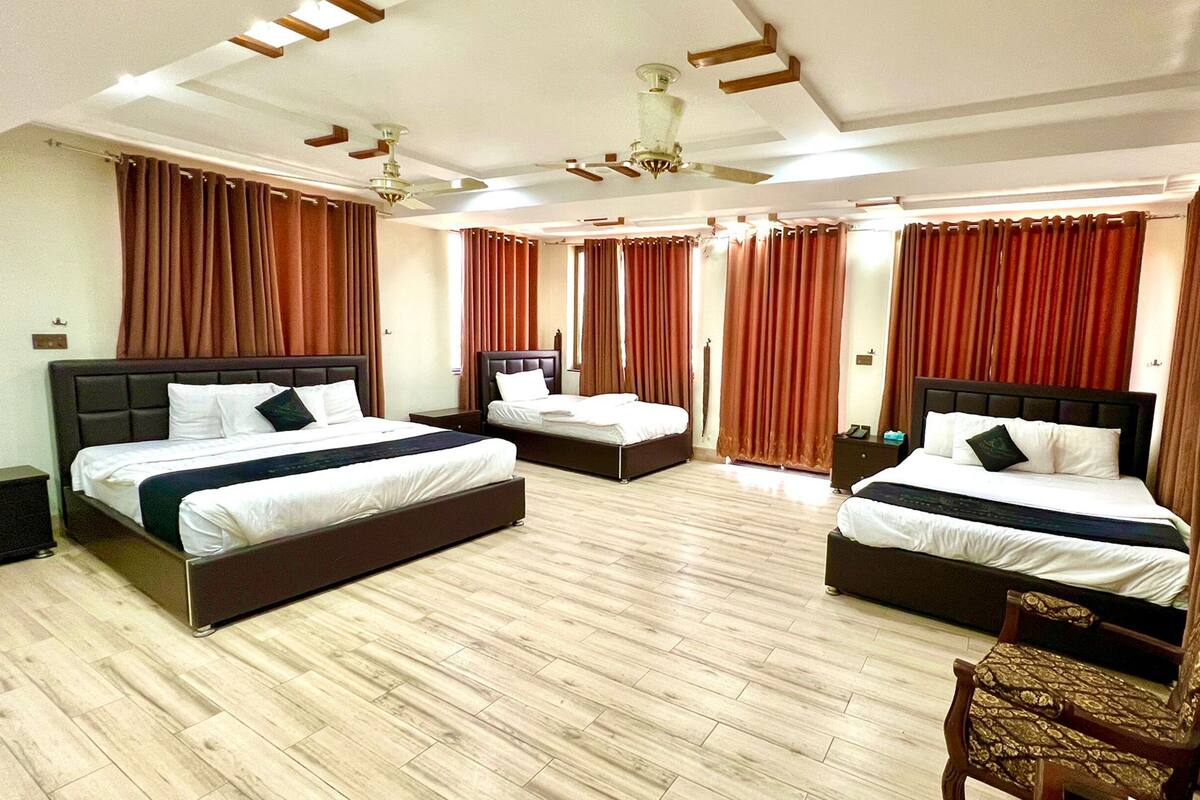 Quarto de hotel com duas camas, uma escrivaninha e uma cadeira.