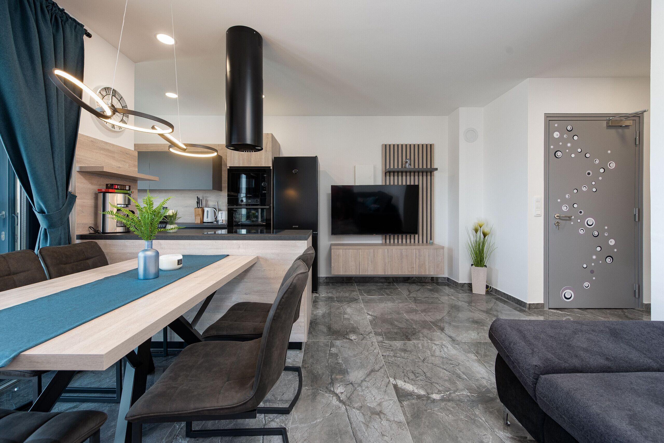Uma sala de estar moderna com área de refeições, cozinha e televisão na parede.