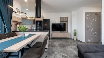 Uma sala de estar moderna com área de refeições, cozinha e televisão na parede.
