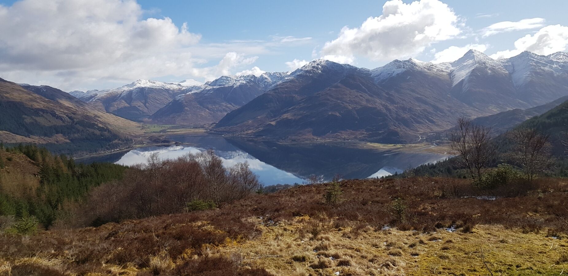 Paisagem montanhosa com um lago e picos nevados.