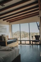 Quarto moderno com uma janela grande, uma cama, uma cadeira e uma mesinha.